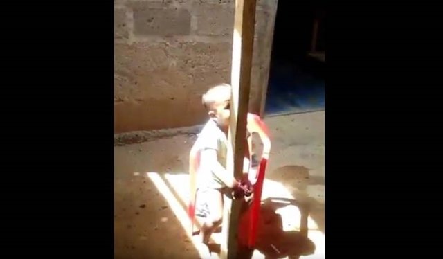 Una madre ata a su hijo a un poste de madera bajo el sol abrasador como ...